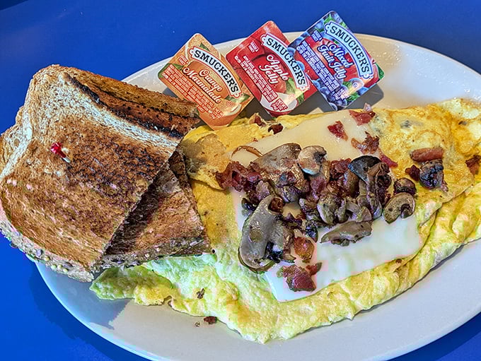 This isn't just an omelet—it's a masterpiece of melted cheese, perfectly sautéed mushrooms, and bacon that would make vegetarians reconsider their life choices.