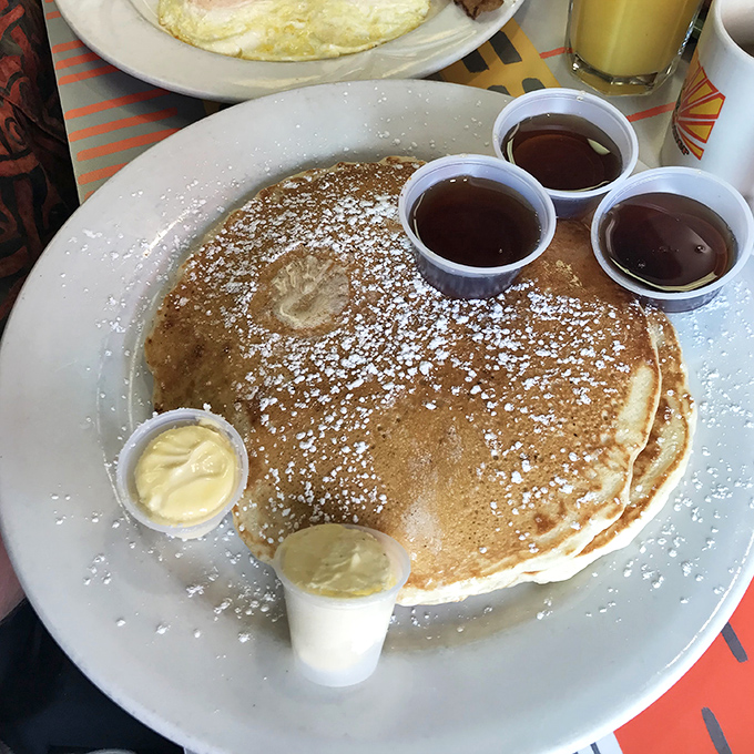 Behold the pancake that requires its own zip code. Dusted with powdered sugar and served with enough syrup cups to float a small boat.