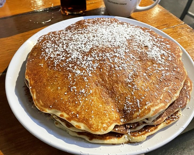 Behold the golden majesty of pancakes dusted with powdered sugar &ndash; each one a fluffy disc of joy waiting to change your morning forever.