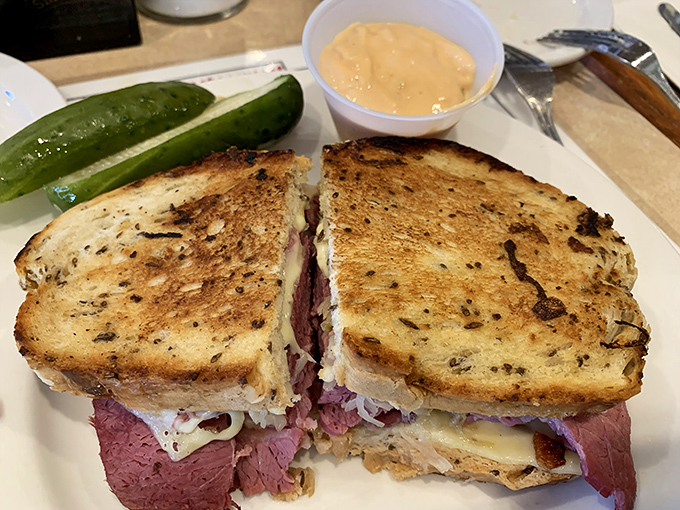 Behold the star attraction: a pastrami sandwich with the perfect meat-to-bread ratio, accompanied by a pickle that means business.