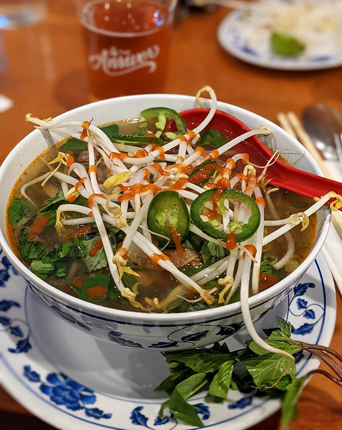 Steam rises from this bowl of pho like a fragrant invitation. Bean sprouts, jalape&ntilde;os, and herbs stand ready for customization.