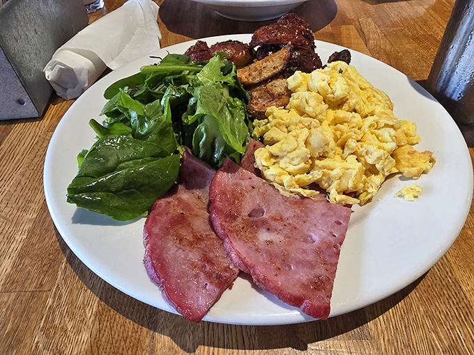 Breakfast perfection on a plate: scrambled eggs that look like clouds, ham with just the right caramelization, and greens to pretend you're being virtuous.