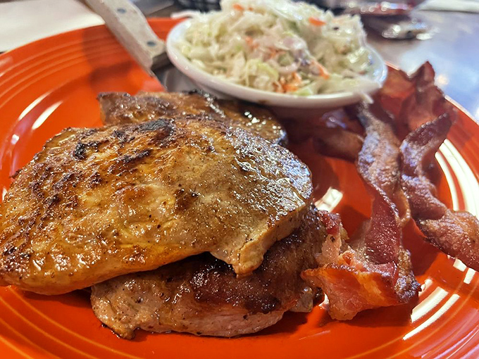 Behold the star of our show: perfectly seared pork chops with that caramelized exterior that makes time stop. Served with coleslaw and bacon because... why not?