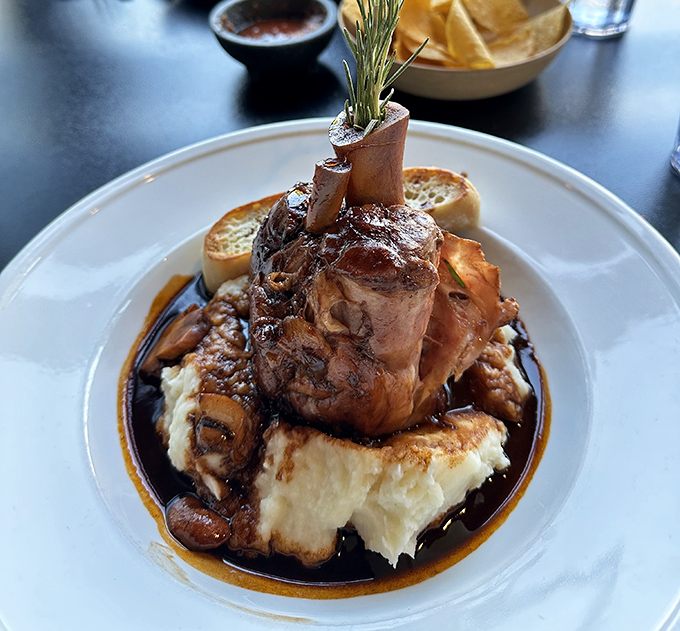 Behold the pork osso bucco in all its glory, perched majestically atop creamy mashed potatoes like edible architecture.