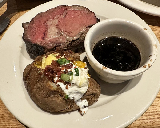 The star of the show: perfectly pink prime rib alongside a loaded baked potato and au jus. This isn't just dinner&mdash;it's a celebration on a plate.
