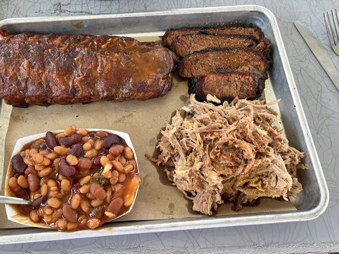 Barbecue perfection on a tray: ribs with that mahogany bark, brisket with the telltale smoke ring, pulled pork, and those legendary beans.