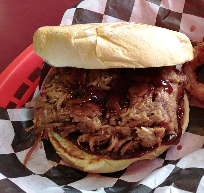 This pulled pork sandwich isn't just food; it's an architectural marvel of smoke-kissed meat that somehow manages to stay on the bun.