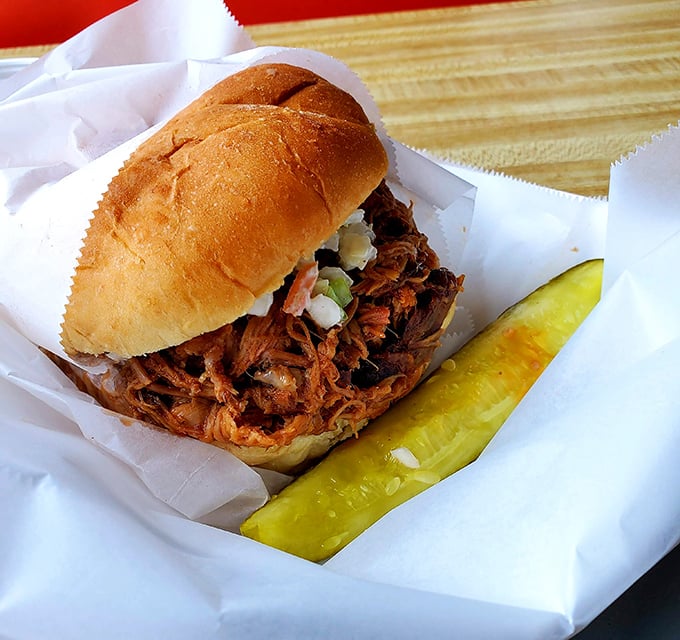 The pulled pork sandwich in all its glory&mdash;tender strands of smoky meat cradled in a soft bun with that pickle sidekick.