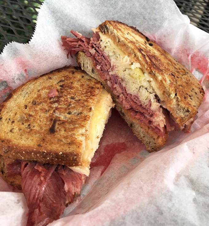 Behold the Reuben in its natural habitat—perfectly grilled rye embracing corned beef and sauerkraut in a dance as old as time.