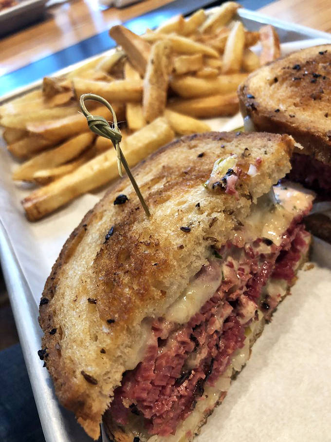 The Reuben in all its glory&mdash;layers of smoky meat, melted cheese, and tangy goodness between perfectly grilled rye. This isn't a sandwich; it's architecture.