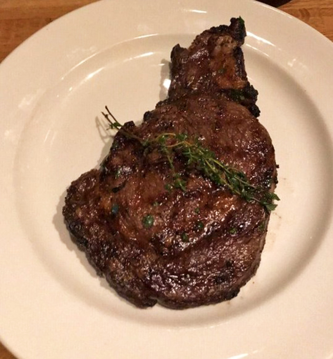 Behold the ribeye in all its glory &ndash; a perfect crust giving way to juicy tenderness. That sprig of thyme isn't garnish, it's a victory flag.