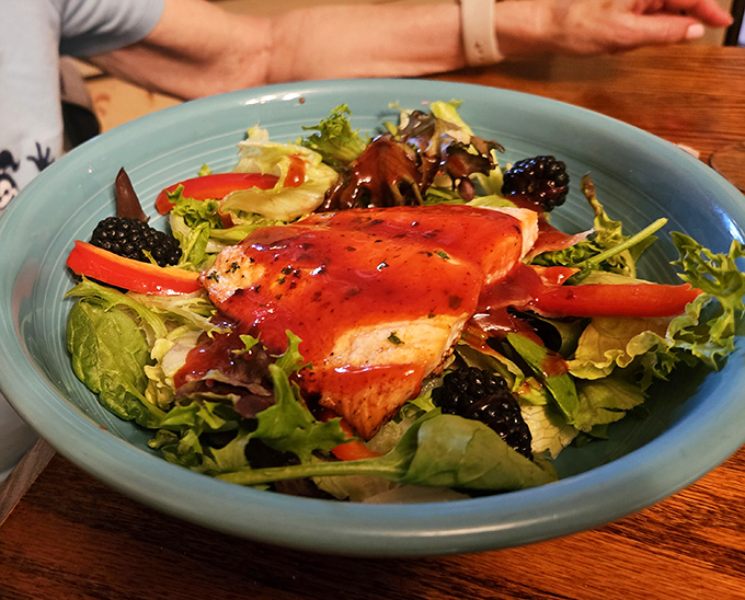 The legendary salmon salad arrives like a sunset on a plate. Fresh greens, juicy berries, and that perfectly glazed fish&mdash;worth every mile of the drive.