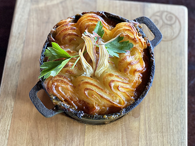 The shepherd's pie arrives like a golden-crowned monarch, its perfectly piped potato peaks hiding a kingdom of savory treasures beneath.