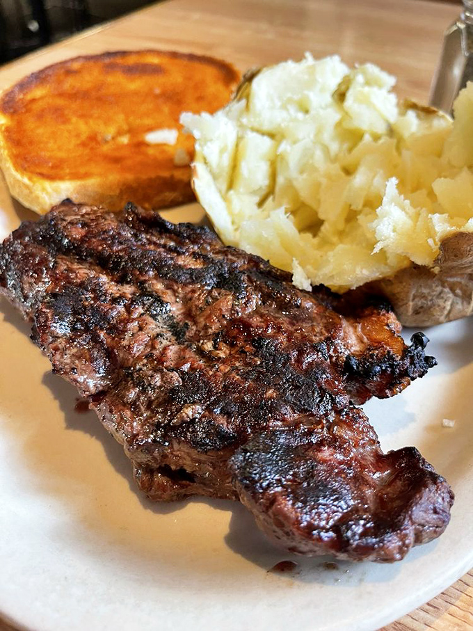 A perfectly charred steak alongside a baked potato that's practically bursting at the seams. That cheese toast isn't just a side&mdash;it's a supporting actor worthy of an Oscar.