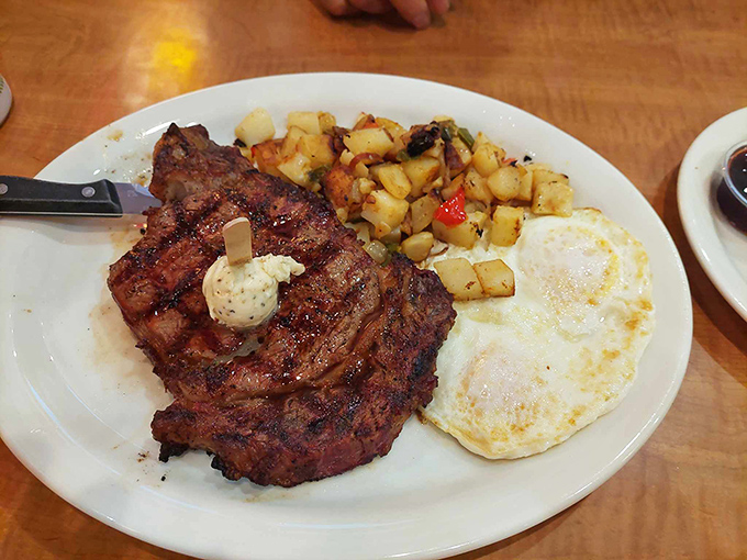 Behold the star of the show &ndash; a wood-smoked steak with perfect grill marks, accompanied by sunny-side-up eggs and home fries that could make a potato proud.