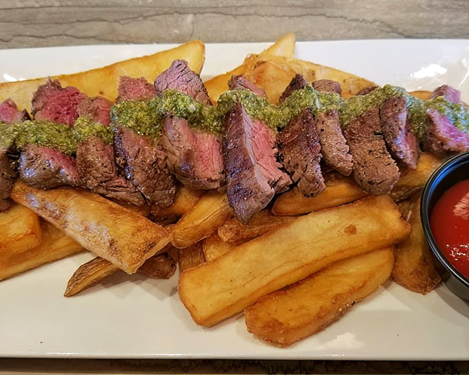 Behold the star attraction: perfectly seared steak slices resting on golden frites, with a vibrant chimichurri that adds just the right punch of herbaceous flavor.