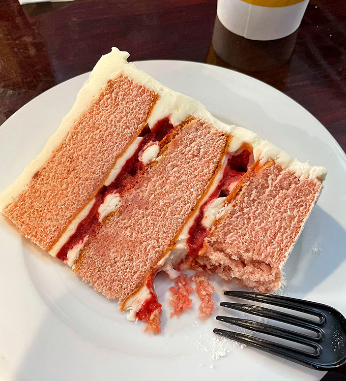 The strawberry cake that launched a thousand return visits. Three perfect layers of pink paradise that make grown adults consider licking the plate clean.
