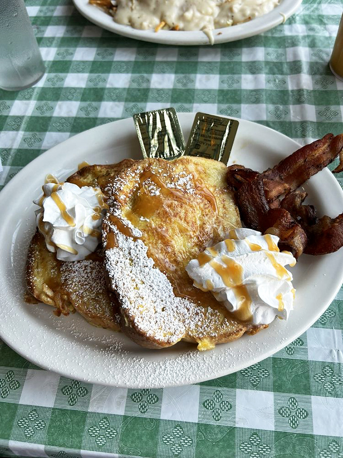 French toast that's dressed for success with whipped cream, caramel drizzle, and bacon standing guard on the side.