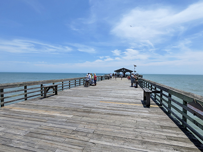 The fishing pier stretches into tomorrow while folks practice the ancient art of patience with a pole.