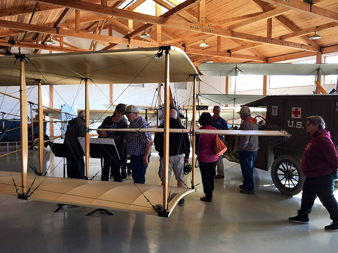 Visitors gather around a fragile WWI-era biplane, marveling at how these canvas-and-wood contraptions changed warfare forever.