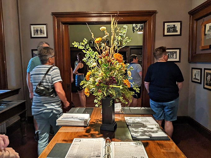 Castle explorers examine historical displays while surrounded by vintage photographs. The flower arrangement seems to be saying, "Yes, you're still in Missouri."