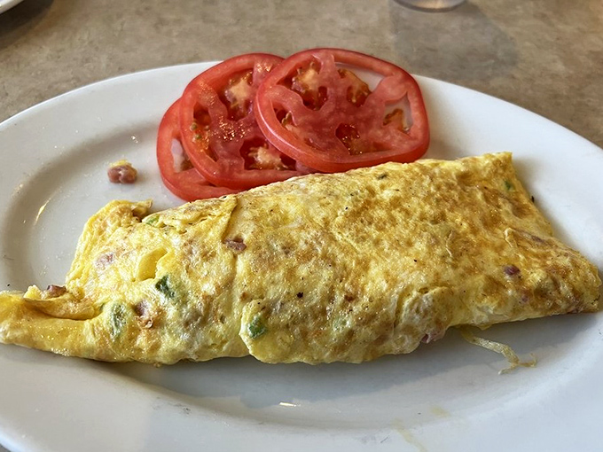 This Western omelet doesn't just whisper "good morning" – it belts it out like Springsteen at the encore, with perfectly cooked eggs cradling savory fillings alongside fresh tomato slices.