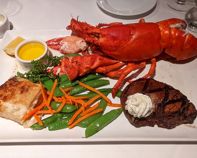 Surf and turf reaches its ultimate expression: a crimson lobster lounging beside a perfectly seared steak, like ocean royalty meeting land nobility.