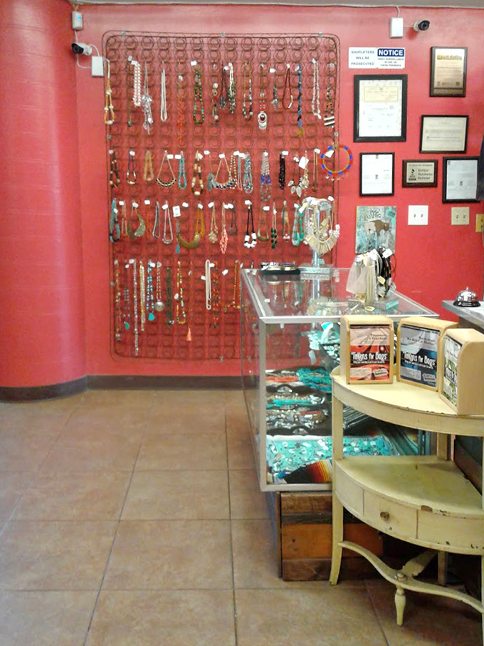 A jewelry lover's paradise against vibrant red walls, where vintage necklaces and contemporary pieces hang like wearable art waiting for their next chapter.