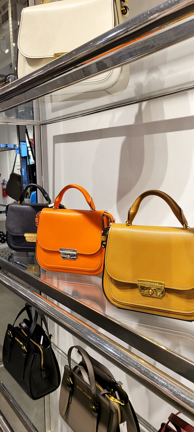 Designer handbags in sunshine colors stand at attention, silently whispering, "You deserve me at this price."