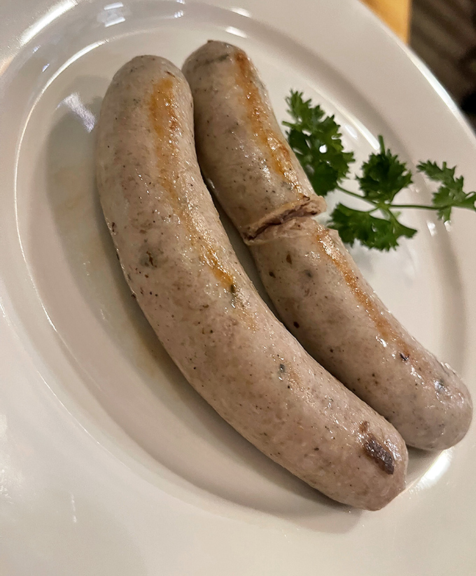 Two bratwursts lounging on a plate like they own the place. That snap when you bite in? Pure sausage symphony.