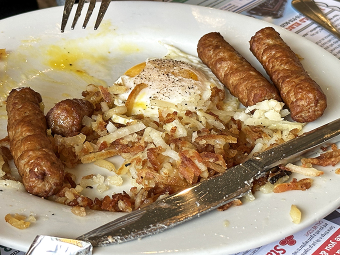 Breakfast perfection: crispy home fries, sausage links, and a sunny-side-up egg that's just waiting for that first glorious fork pierce.