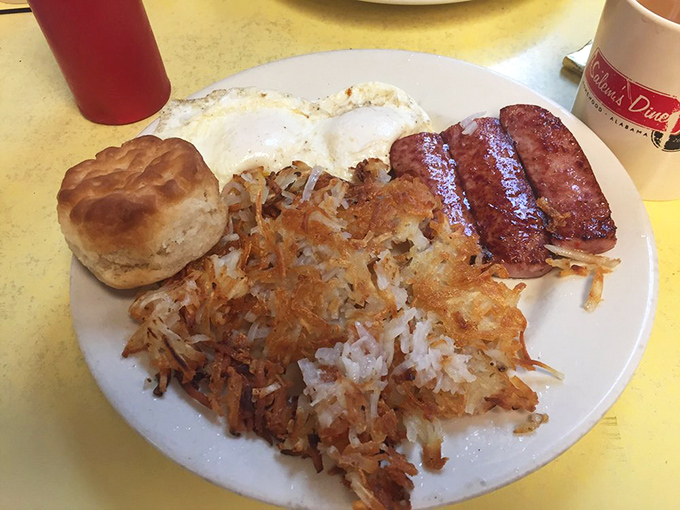 Breakfast nirvana on a plate: crispy hashbrowns with that perfect golden crust, eggs cooked just right, and a biscuit that would make your grandmother both proud and jealous.