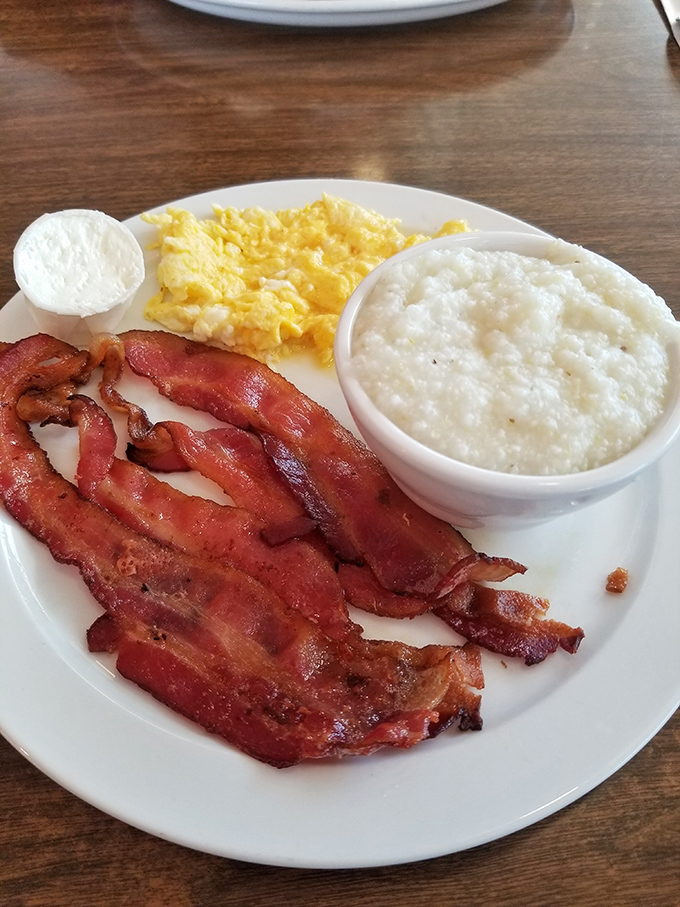 Breakfast perfection on a plate: crispy bacon, fluffy eggs, and grits that would make a Southerner homesick. The holy trinity of morning bliss.