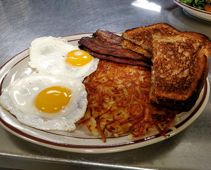 Breakfast perfection on a plate: sunny-side up eggs with yolks ready to burst, hash browns crisped to golden perfection, and toast that's achieved that magical butter-to-crunch ratio.