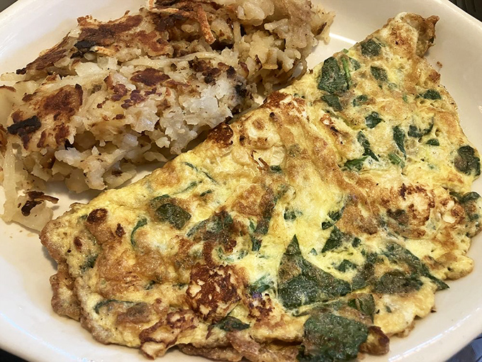 This spinach omelette isn't just breakfast—it's a morning masterpiece with perfectly crisped hash browns playing the essential supporting role.
