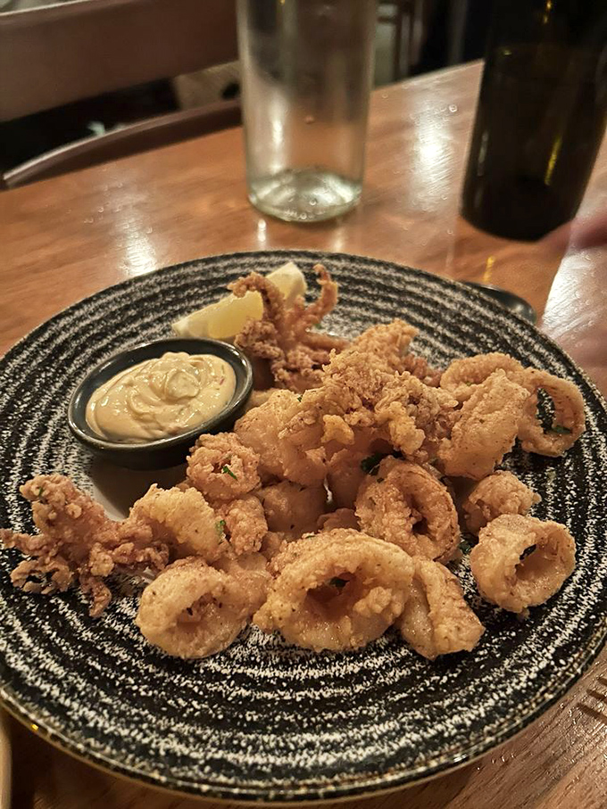 Golden-fried calamari that shatters with each bite – tender within, crispy without. The kind that makes you forget all those rubbery pretenders from your past.