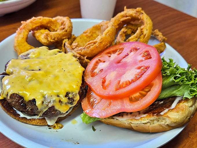 Behold the burger that launches road trips. That perfect cheese melt cascading down the patty is what food dreams are made of. The onion rings? Supporting actors deserving their own spinoff.