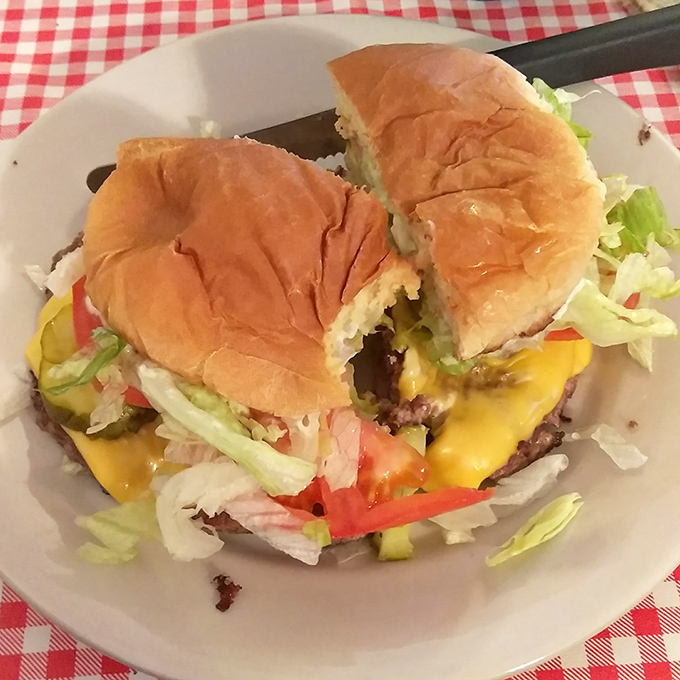 Behold the star attraction: a burger that requires strategic planning to eat. That melty cheese cascade isn't just delicious&mdash;it's edible architecture.