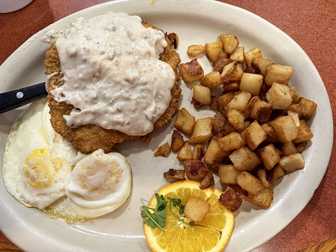 Chicken fried steak swimming in creamy gravy alongside golden potatoes&mdash;proof that sometimes the best morning therapy comes on a white plate.