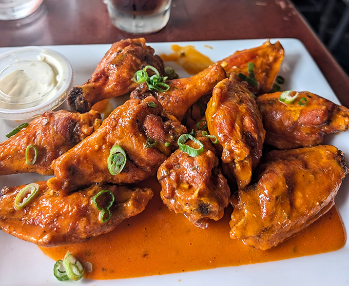 These aren't just wings; they're flavor bombs dressed in their Sunday best, glistening with sauce and topped with a confetti of green onions.