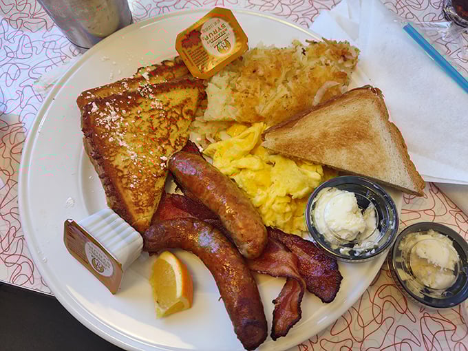 French toast, eggs, sausage, and hash browns arranged on one plate like a breakfast symphony conducting itself.