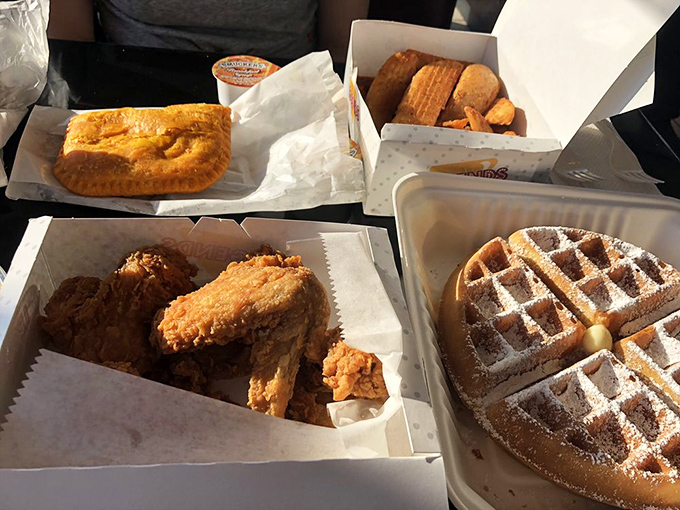 The holy trinity of comfort food: golden fried chicken, perfectly dusted waffles, and what appears to be a savory pastry. Breakfast, lunch, or dinner? Yes, please.