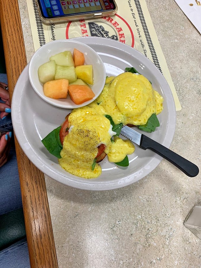 These Eggs Benedict aren't just perfectly executed—they're a masterclass in hollandaise technique. The bright side of fresh fruit provides the illusion of virtue alongside this morning indulgence.