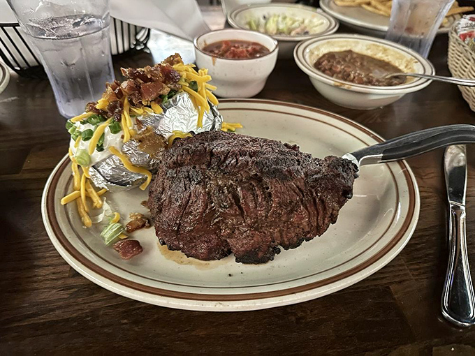 Behold the filet mignon in its natural habitat&mdash;perfectly charred outside, blushing pink inside. That loaded potato is playing a supporting role worthy of an Oscar.