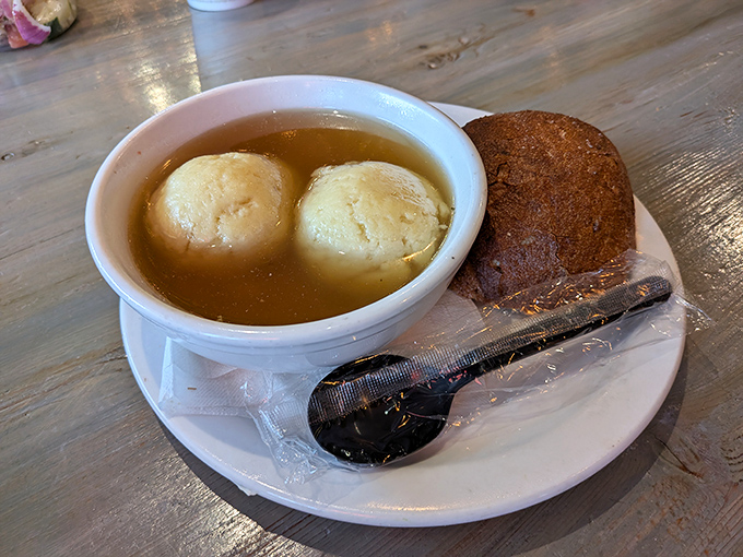 Two golden matzo balls float in amber broth like edible life rafts, ready to rescue you from whatever ails you.