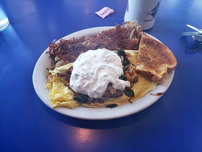 This isn't just an omelet&mdash;it's an architectural marvel of eggs, fillings, and that glorious crown of sour cream. Crispy hash browns standing guard alongside.