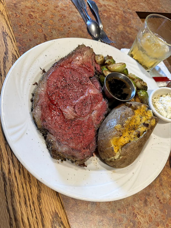 Behold the star of the show: prime rib so perfectly pink it should have its own Instagram account, accompanied by a baked potato that knows its supporting role.