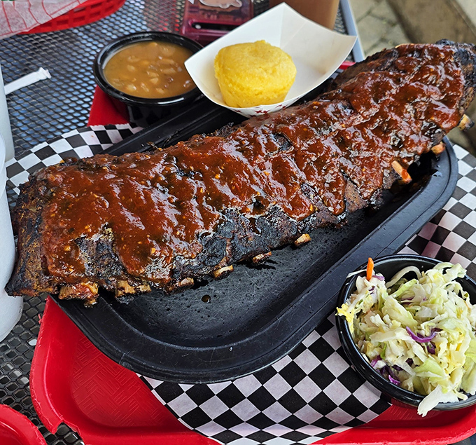 Behold, the star of the show: ribs glistening with sauce, flanked by golden cornbread and creamy slaw&mdash;a holy trinity of BBQ perfection.