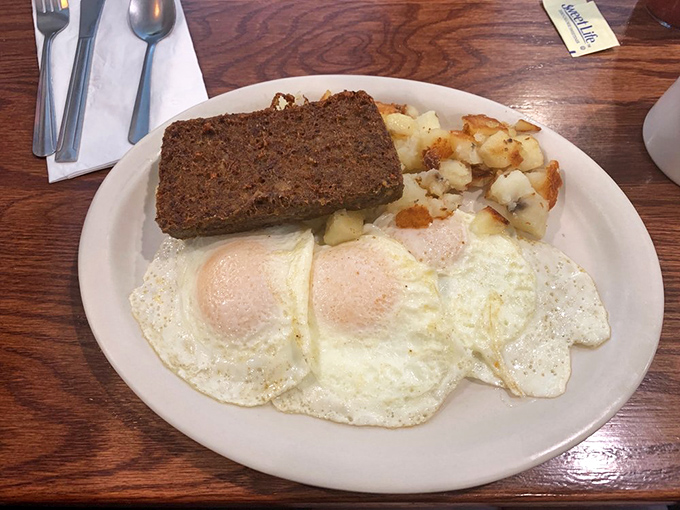 Behold the holy trinity of breakfast perfection: crispy-edged scrapple, sunny-side-up eggs, and home fries that could make a potato farmer weep with joy.