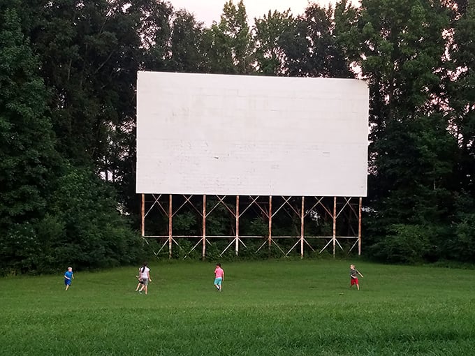 Children play beneath the blank canvas of the screen, creating their own pre-show entertainment.